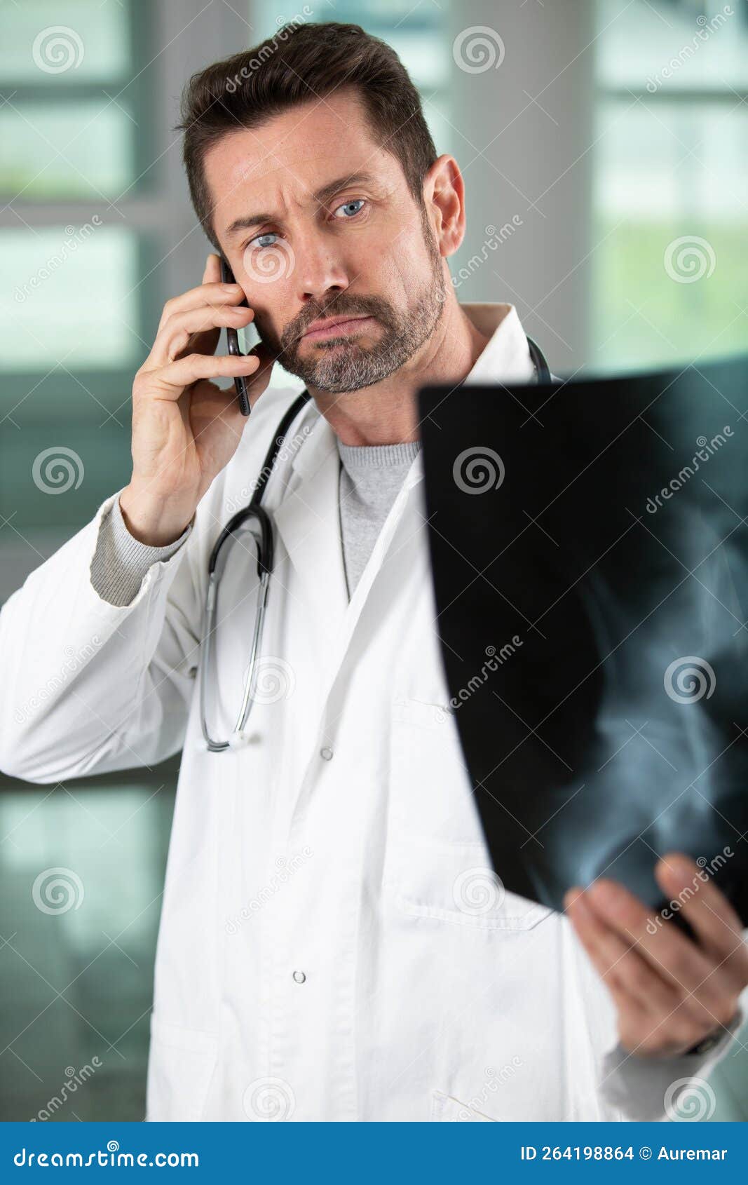 Serious Doctor Looking at X-ray and Making Telephone Call Stock Photo ...
