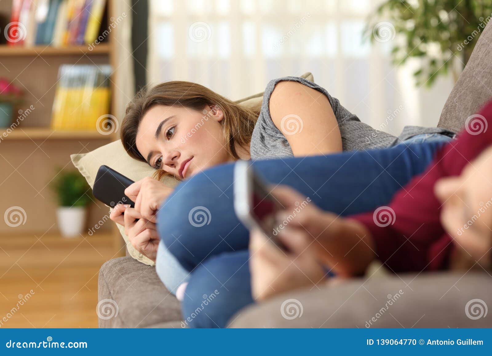Serious Friends Using Their Smart Phones at Home Stock Photo - Image of ...