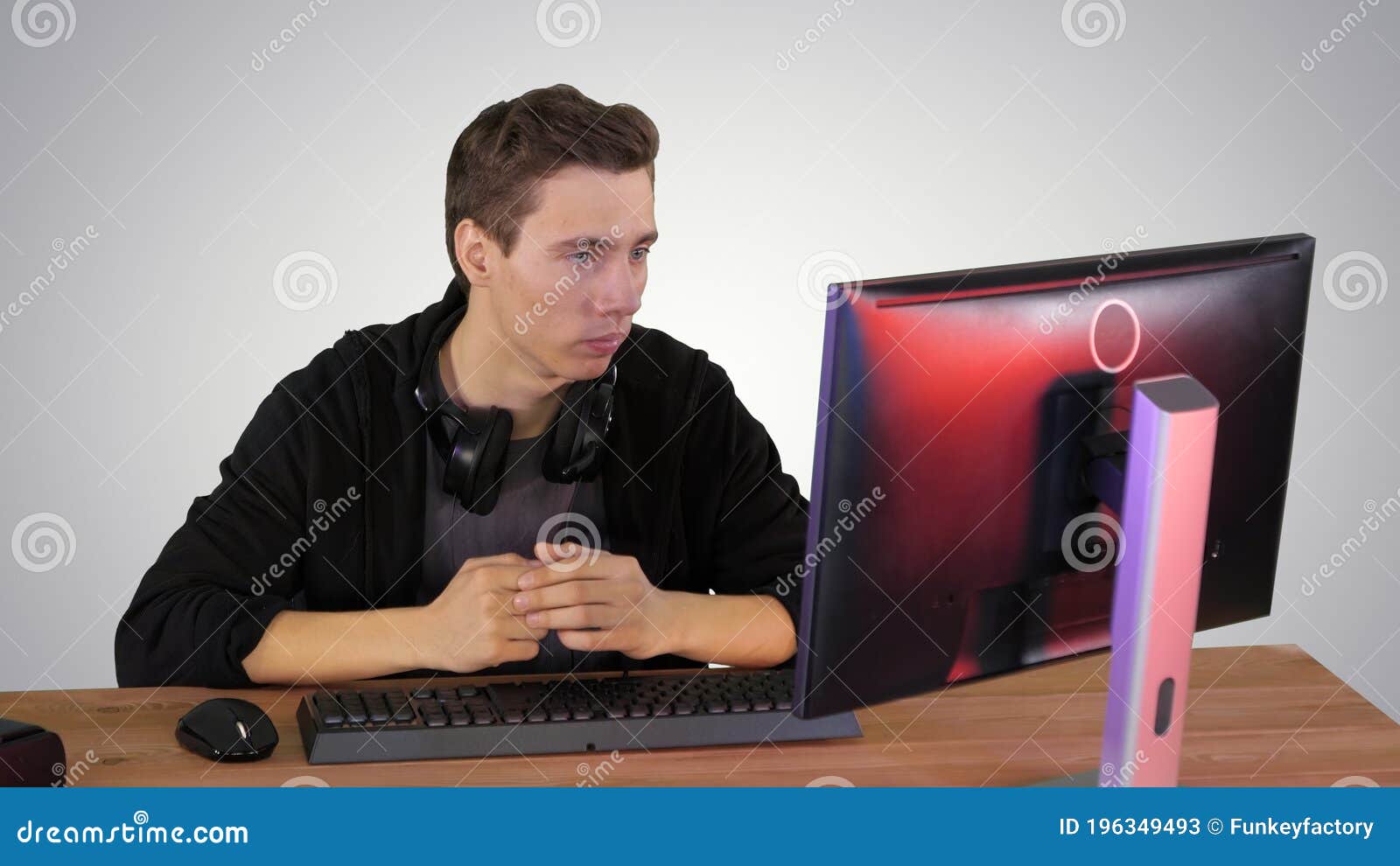 Serious Gamer Sitting at Computer Watching a Game on Gradient Ba Stock ...