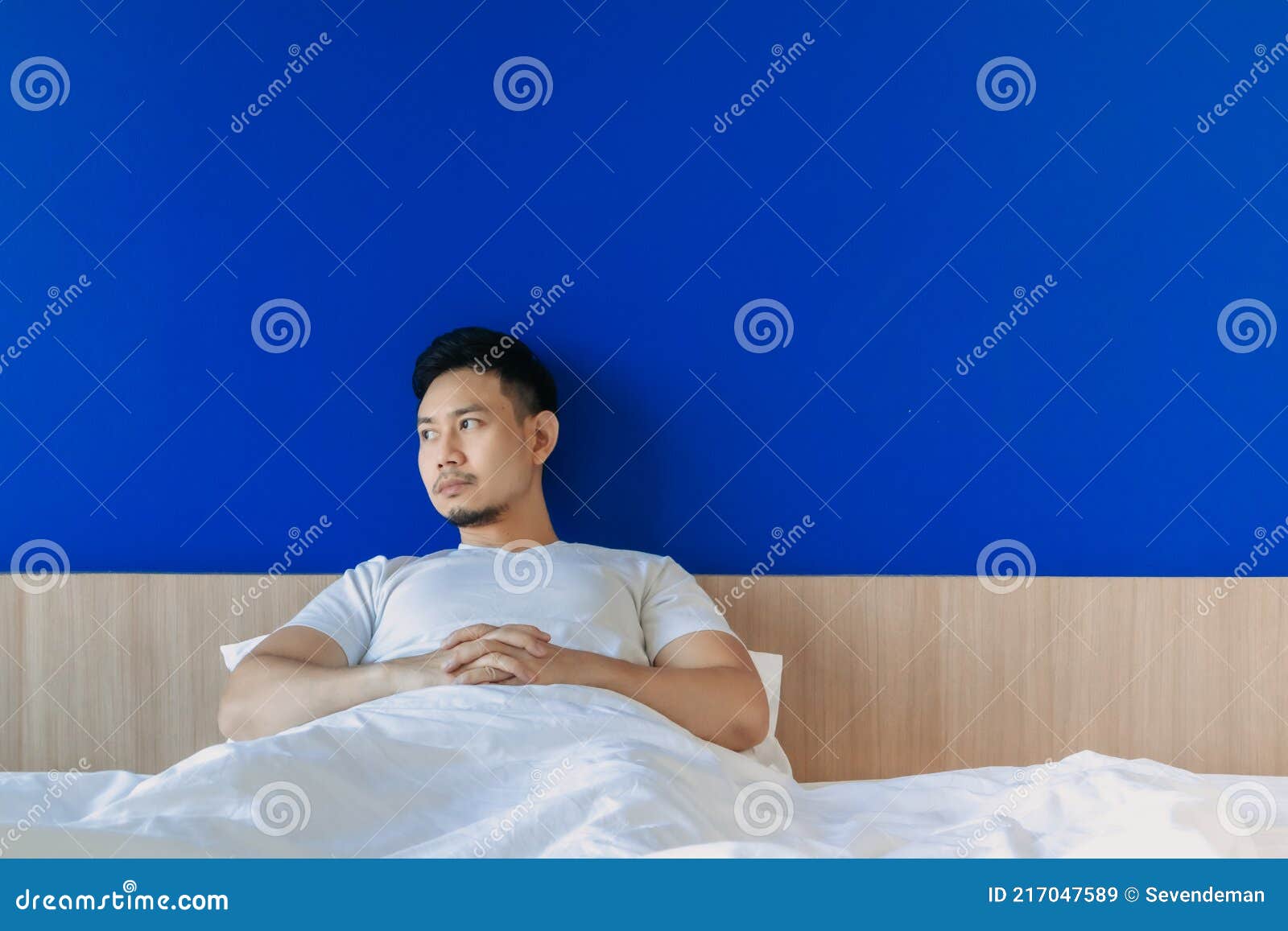 Serious and Grumpy Man Wake Up on the Bed on Blue Space Background ...
