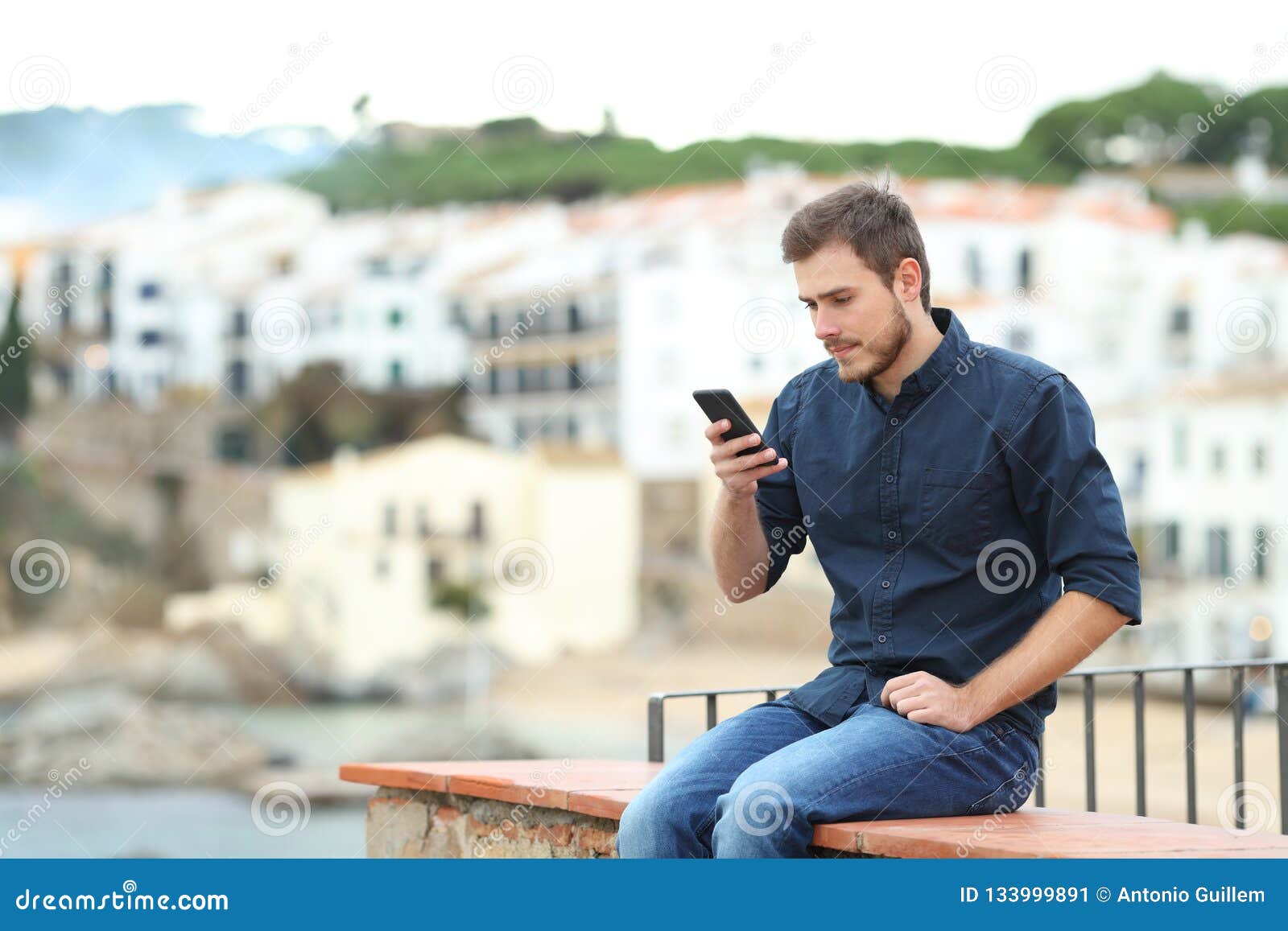 Serious Man Checking Phone on a Ledge on Vacation Stock Image - Image ... Serious Man Checking Phone on a Ledge on Vacation Stock Image - Image ...