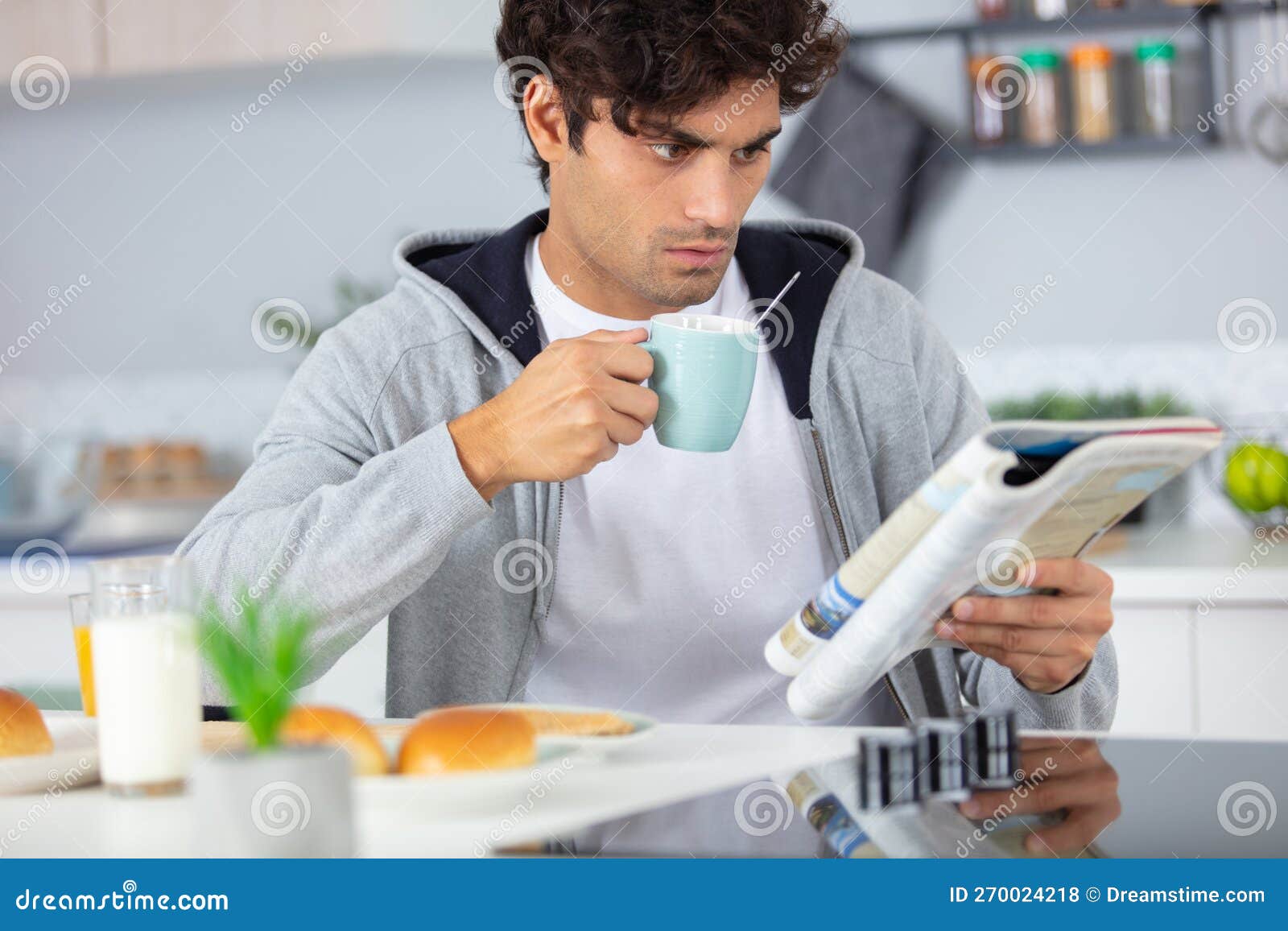 Serious Man in Kitchen Eating Breakfast and Reading Magazine Stock ...