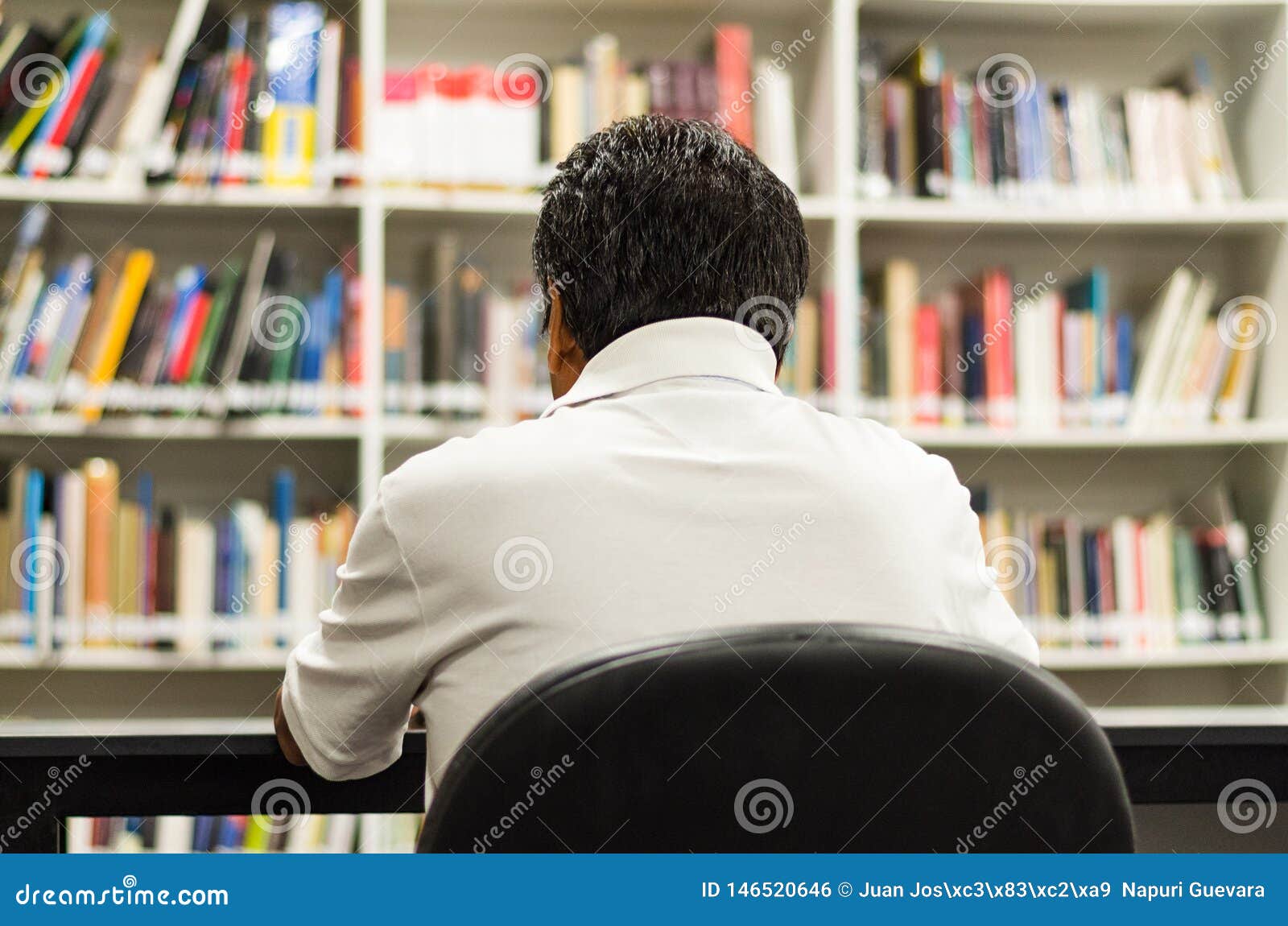 Serious Senior Man Sitting on a Library Bench Writing in His Book ...