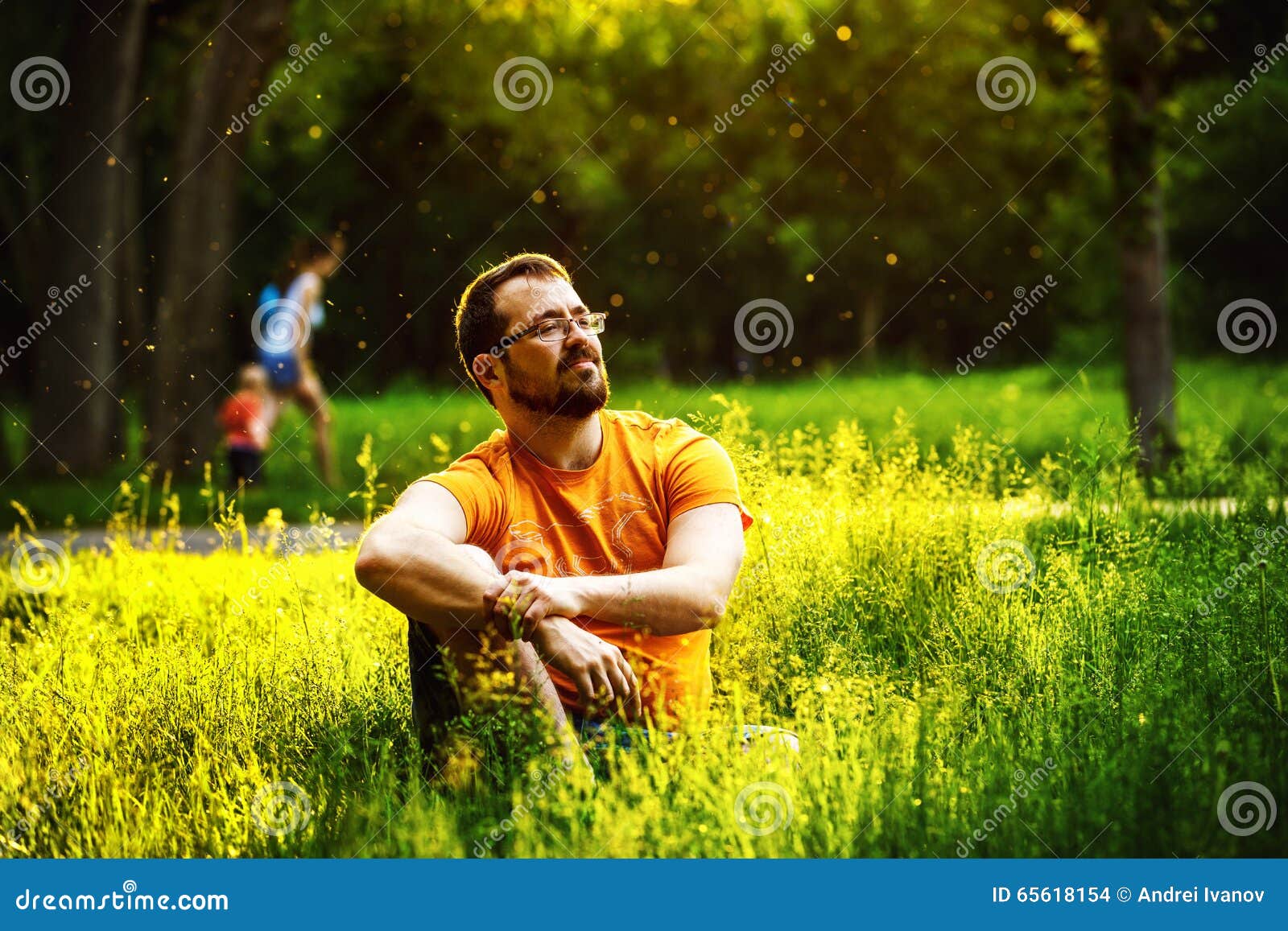 A Serious Thoughtful Man Is Sitting On Green Grass In A Park Stock