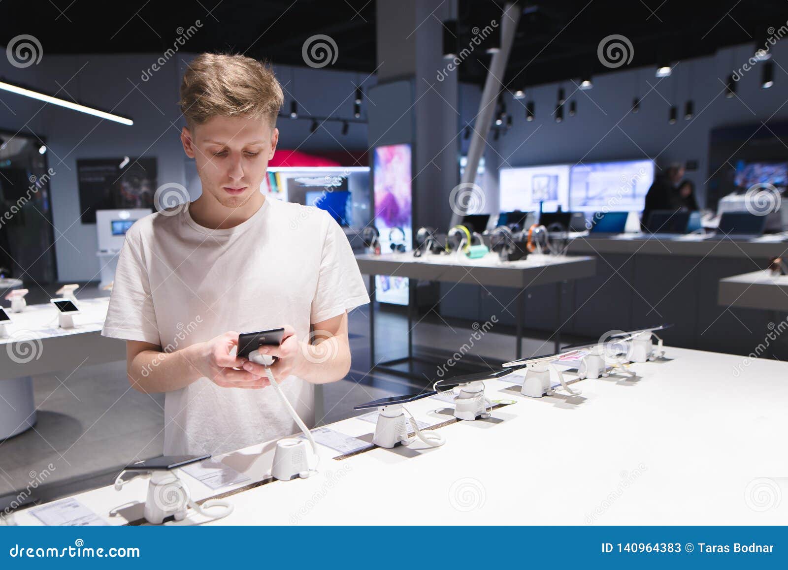 Serious Young Man is Buying a Smartphone in the Electronics Store. Buy ...