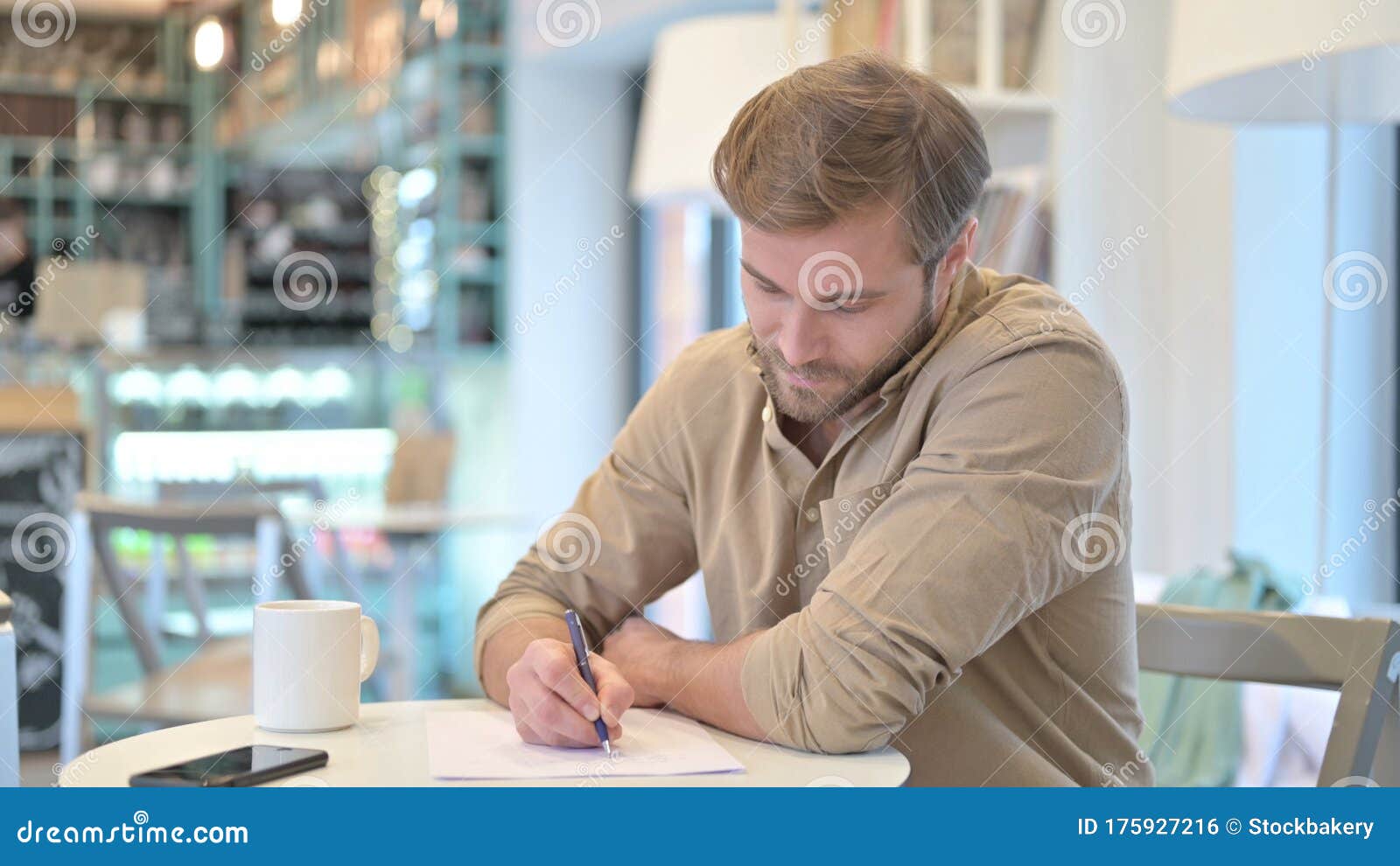 Serious Young Man Doing Paperwork in Cafe Stock Photo - Image of book ...