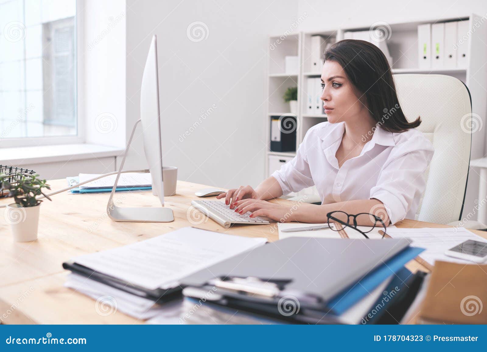 Serious Young Office Manager Looking at Computer Screen while Entering ...