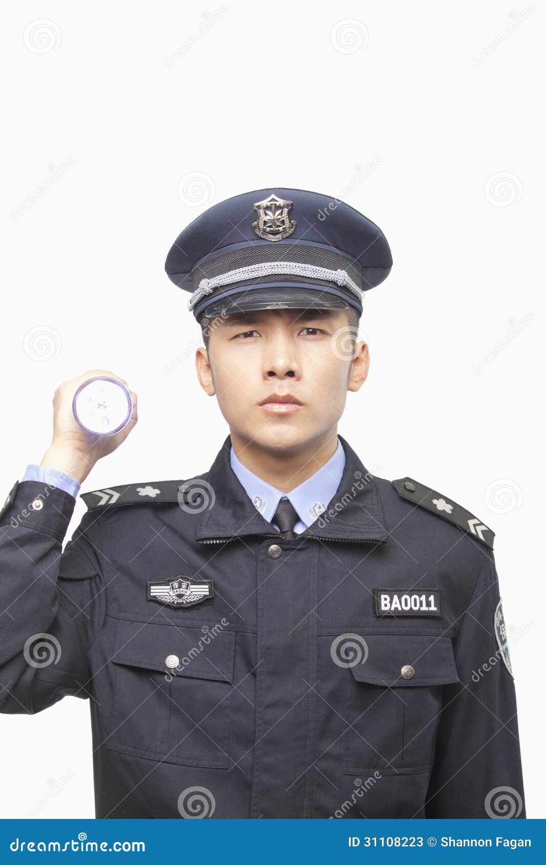 Serious Young Police Officer Shining Flashlight into Camera, Studio ...