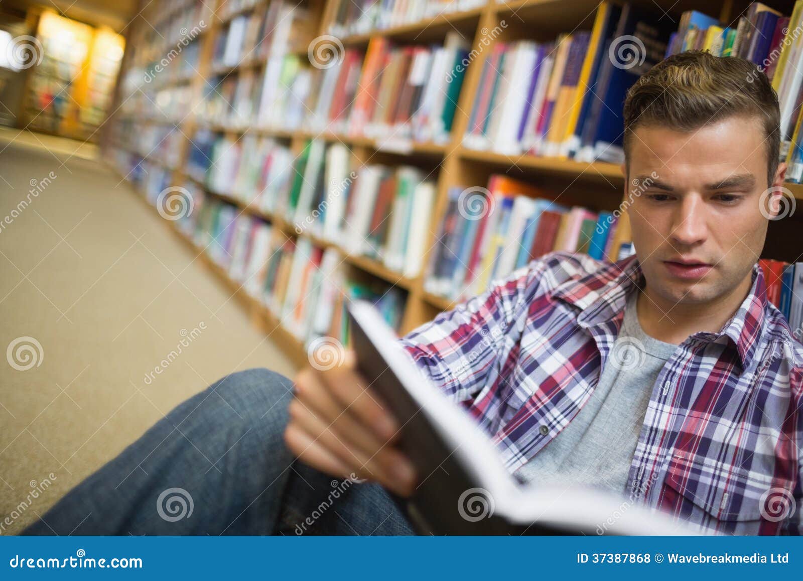 Serious Young Student Sitting on Library Floor Reading Book Stock Photo ...