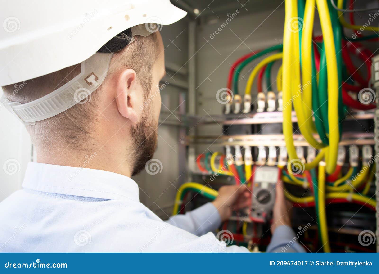 Serviceman Adjusts Fuse Box. Electrician Engineer Measures Voltage in a Power Electrical Cabinet ...