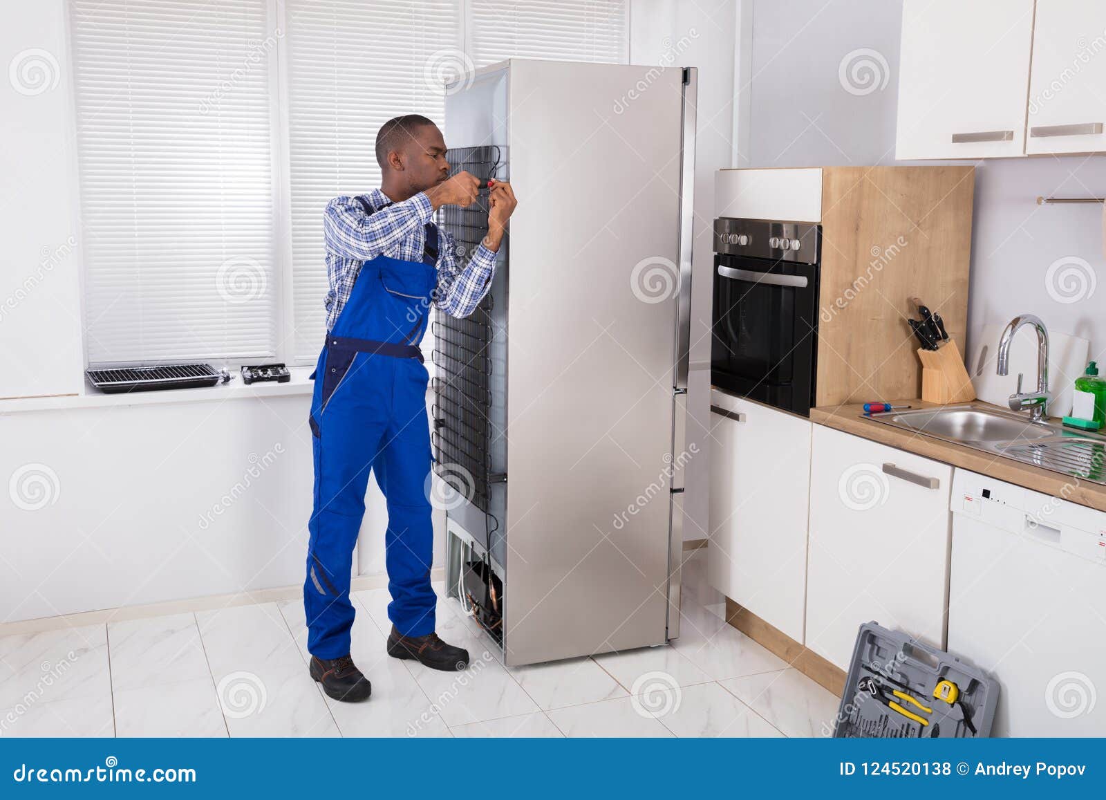 Serviceman in Overall Working on Fridge Stock Photo - Image of african ...