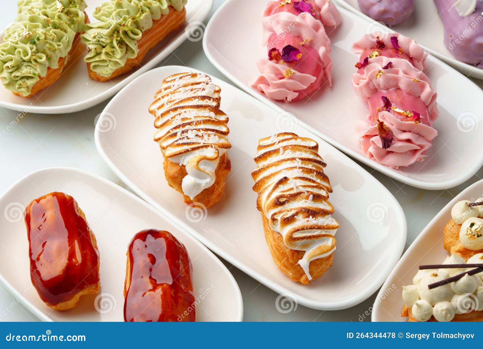 Set of Colored Eclairs with Whipped Cream on White Plates Stock Photo ...
