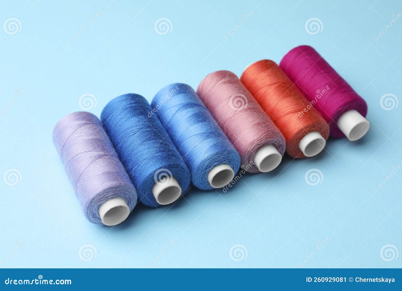 Set of Different Colorful Sewing Threads on Light Blue Background Stock ...