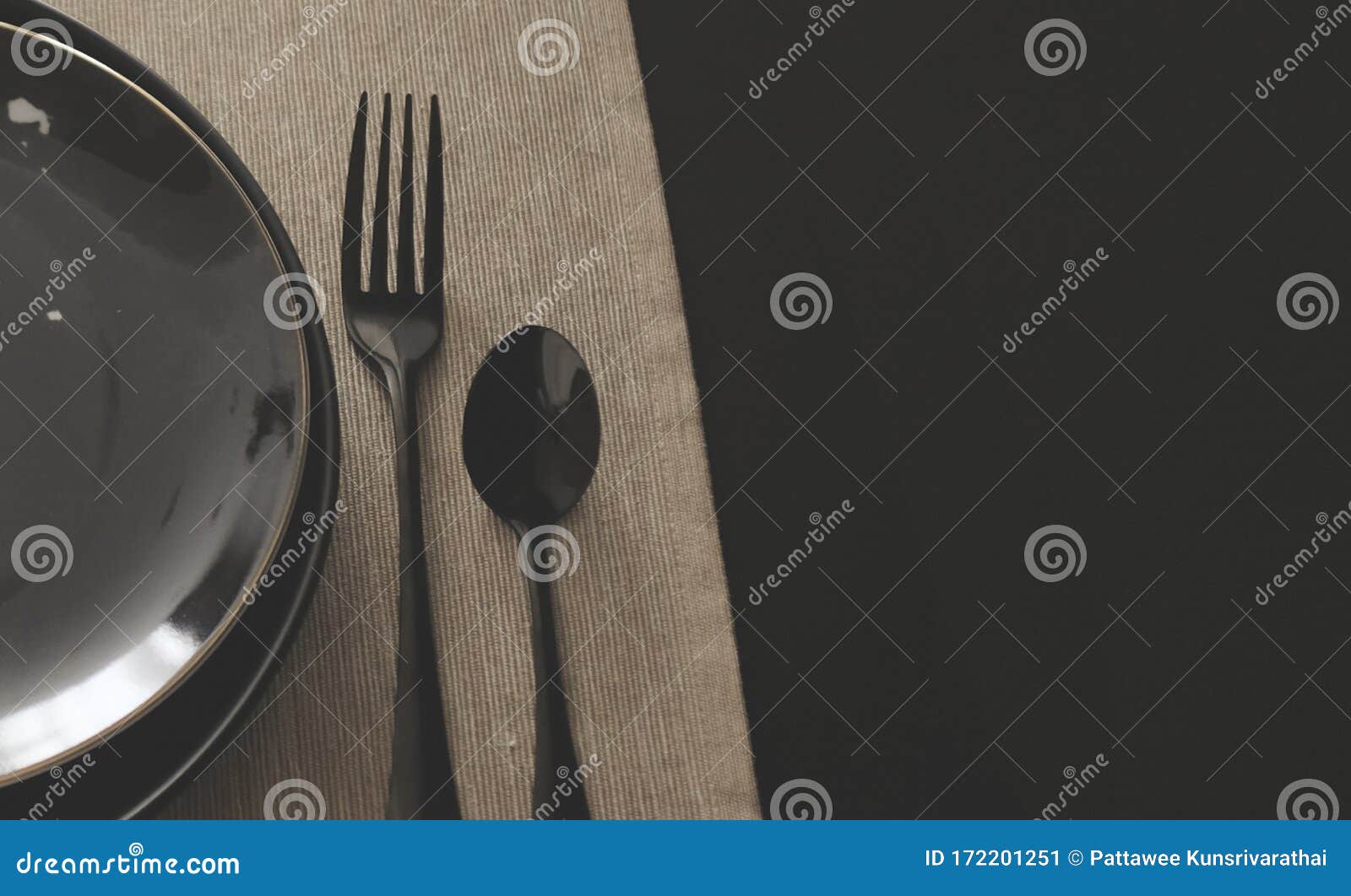 A Set of Set Plates Cutlery on Black Wooden Dinner Table with with Prop ...