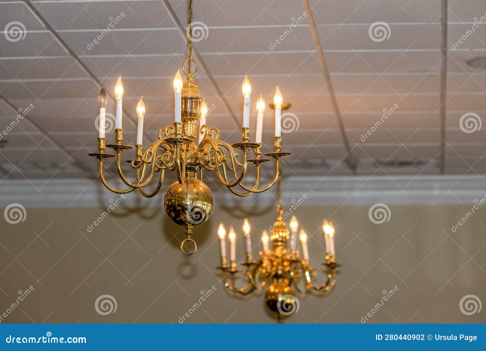 A Set of Two Brass Gold Chandlier Lights Hanging from a Tile Tiled ...