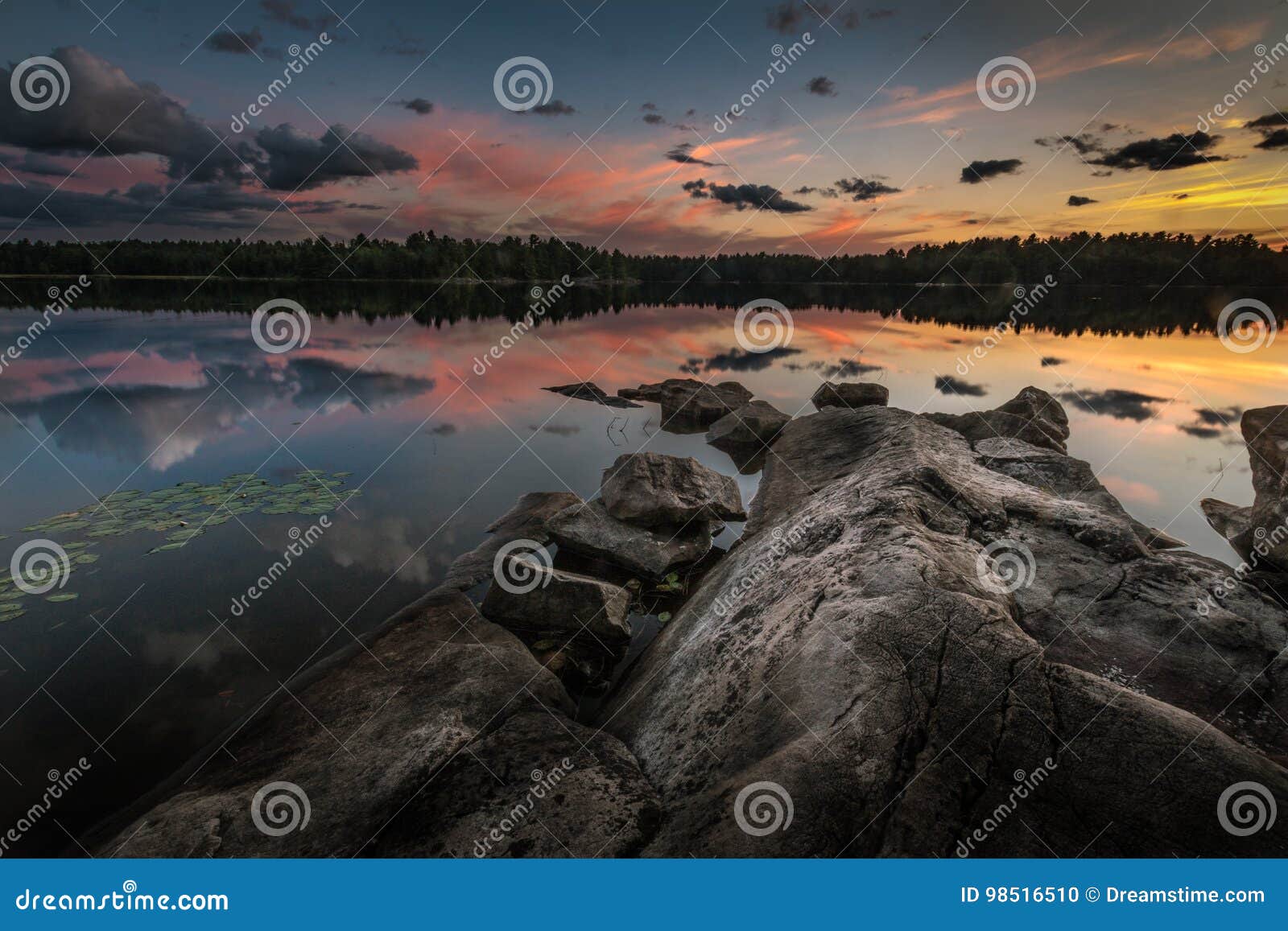 A Setting Sun with Clouds Reflected on a Smooth Lake. Stock Photo ...