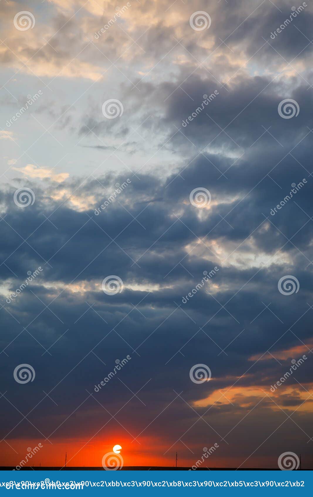 The Setting Sun in Red Against a Background of Blue Clouds and a Sky of ...