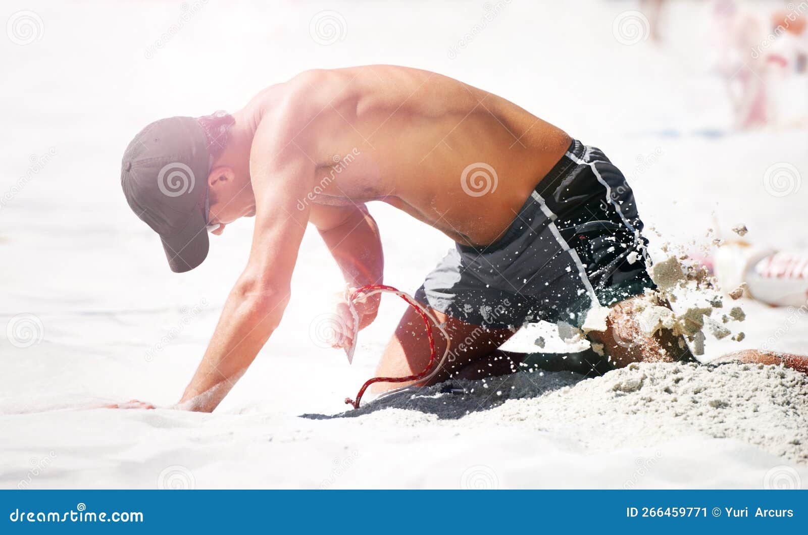 Setting Up at the Beach. a Young Man Digging in the Sand at the Beach ...