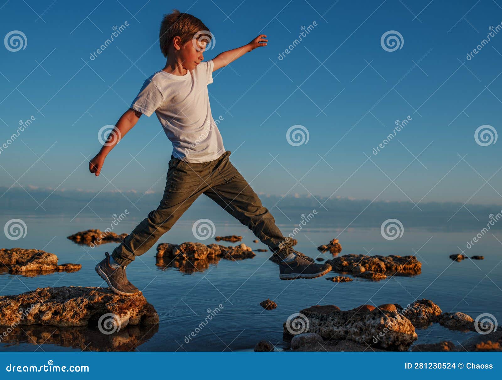 Boy Walking on Stones in the Lake Stock Photo - Image of clouds ...
