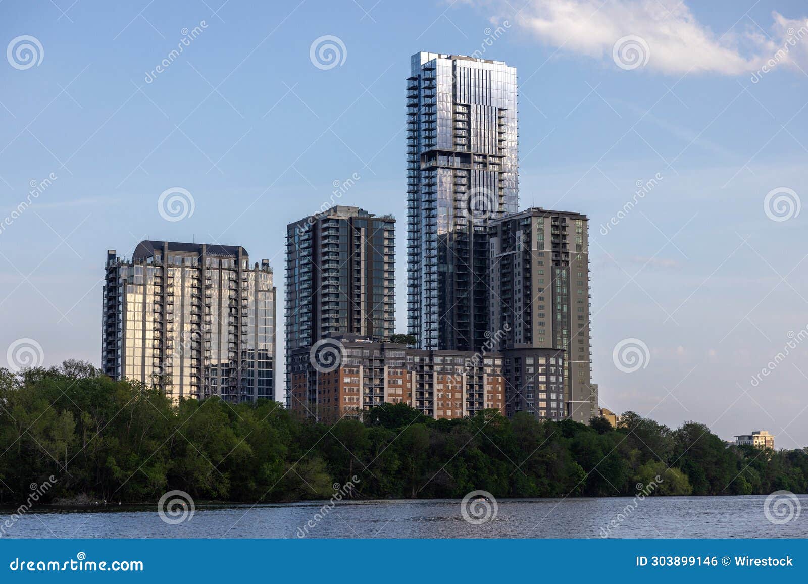 Of Several Tall Buildings in the Distance Behind the Water and Trees ...