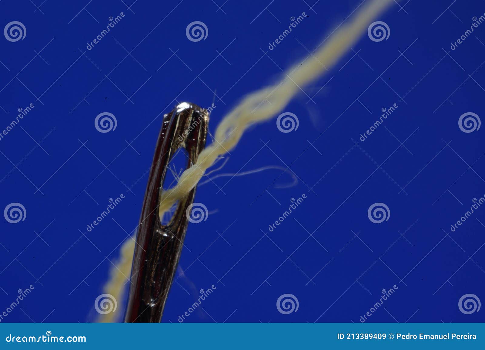 Sewing Needle with a Yellow Thread Passing through the Groove on a Blue ...