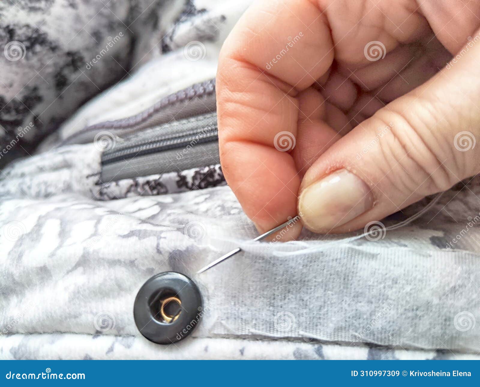 Sewing with a Needle and Thread on a Mottled Spotted Fabric by Hand. a ...