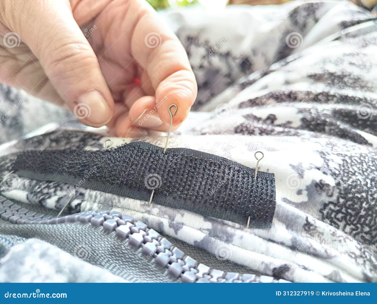 Sewing with a Needle and Thread on a Mottled Spotted Fabric by Hand. a ...