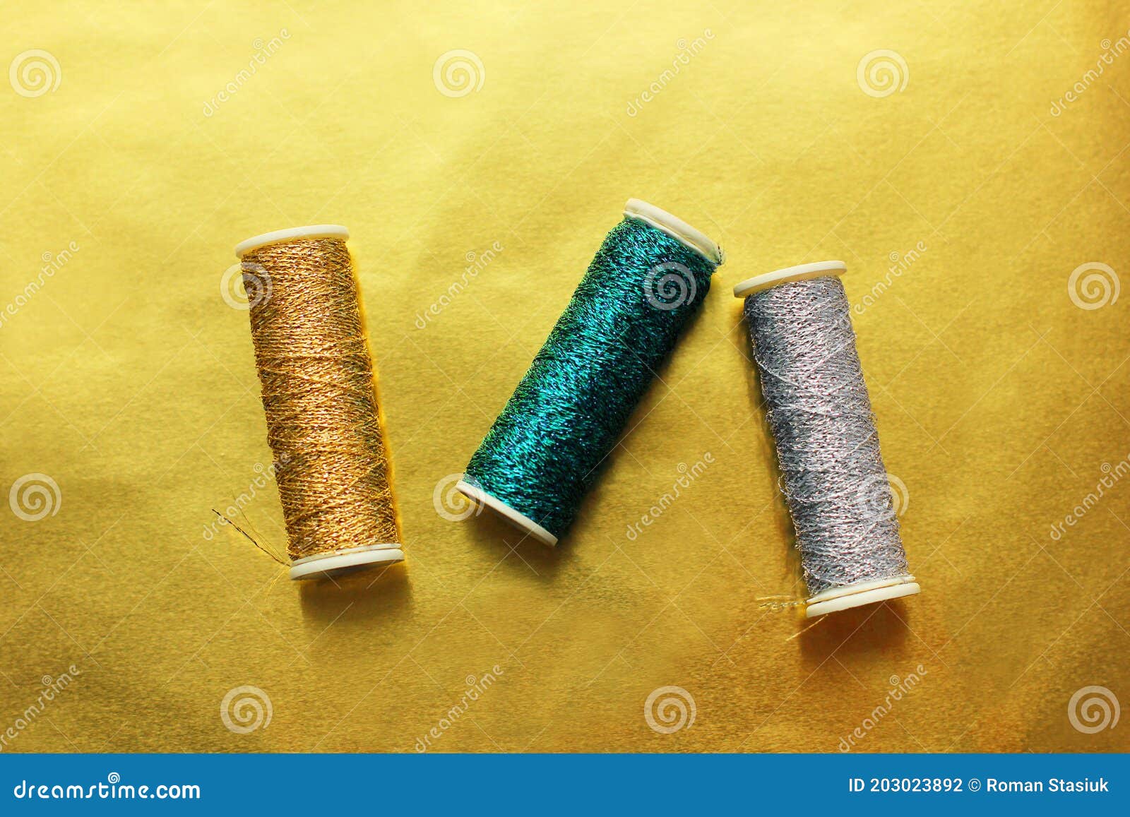 Sewing Threads on a Gold Background. Bright Shiny Threads. Gold and ...