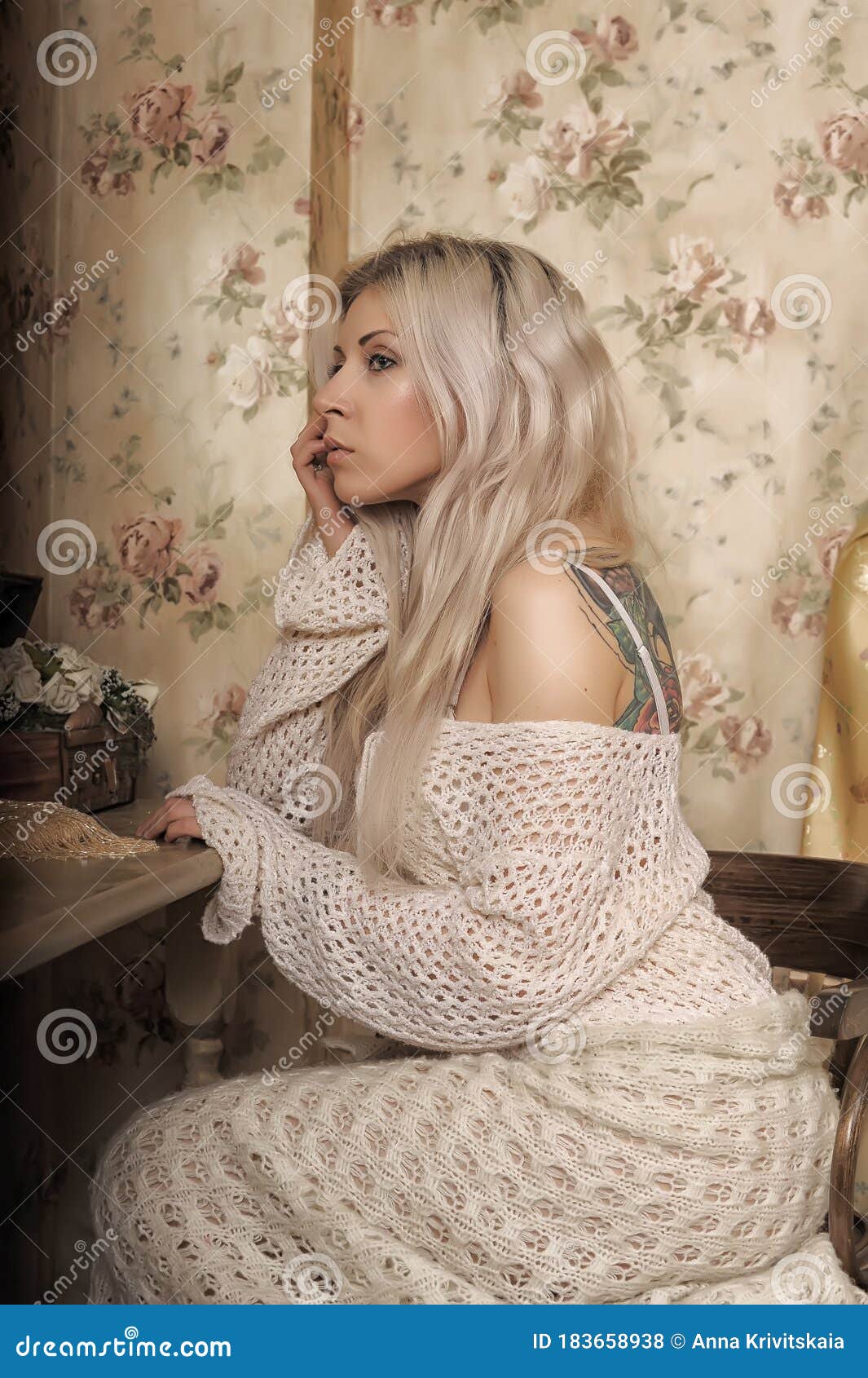 Beautiful Blonde With A White Knitted Sweater Sits At A Table Stock