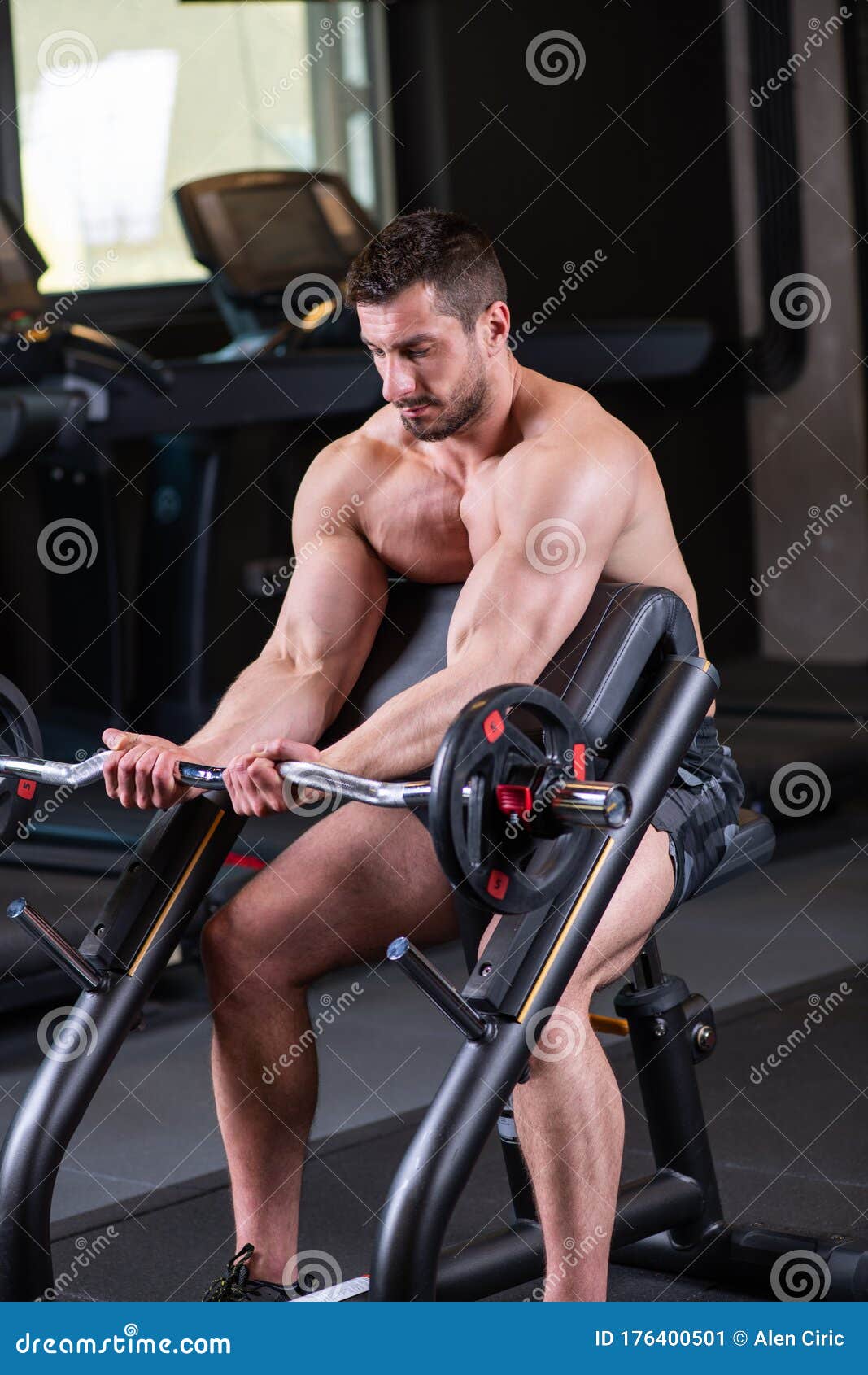 Muscular Man Sitting on the Bench and Doind Biceps Exercise Stock Image ...