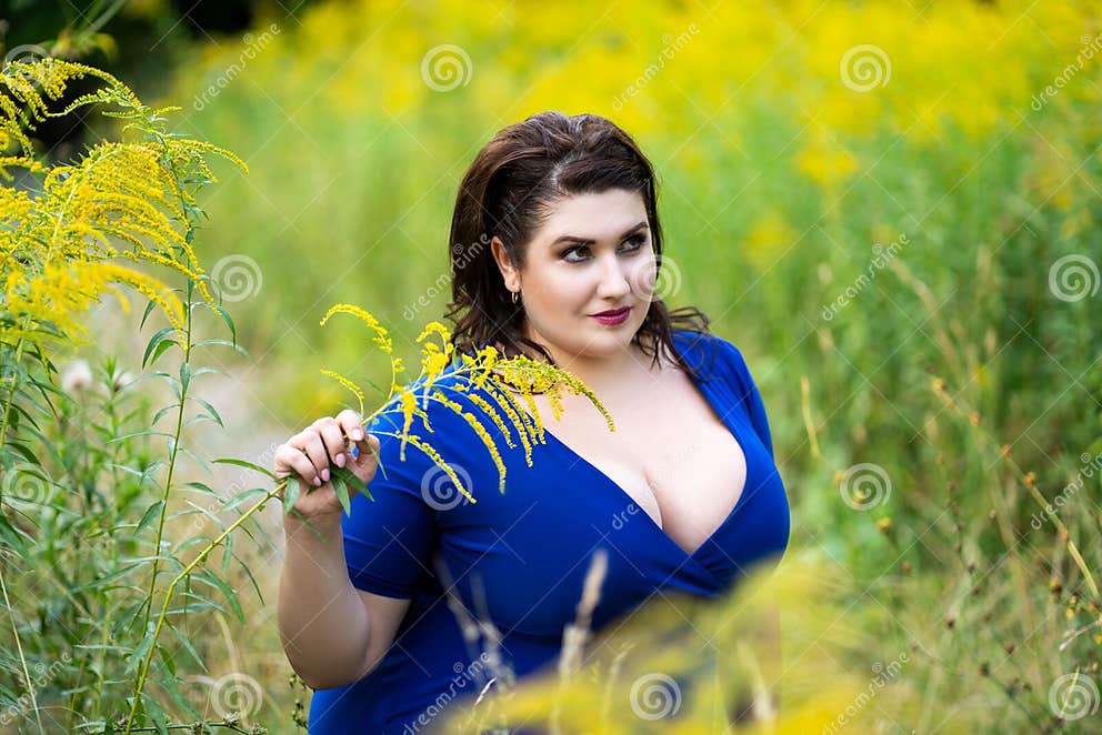 Plus Size Fashion Model In Blue Dress With A Deep Neckline Outdoors