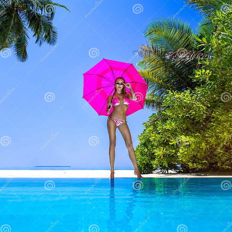 Woman In Bikini With Pink Umbrella Near The Pool At Maldives Tropical