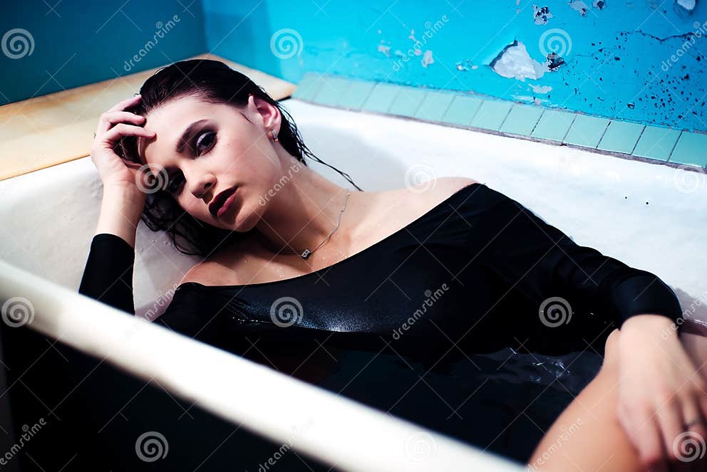 Woman In The Bodysuit In The Bath Bright Light And Colored Water Bare