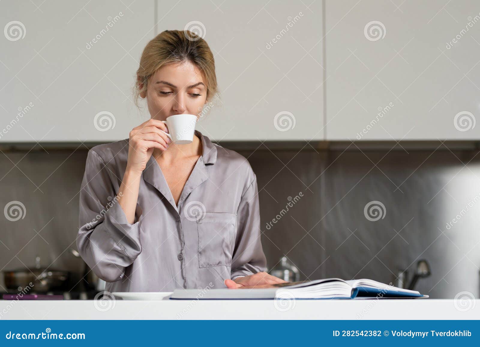 Woman Drink Coffee And Reading Book Or Magazine In The Kitchen Woman