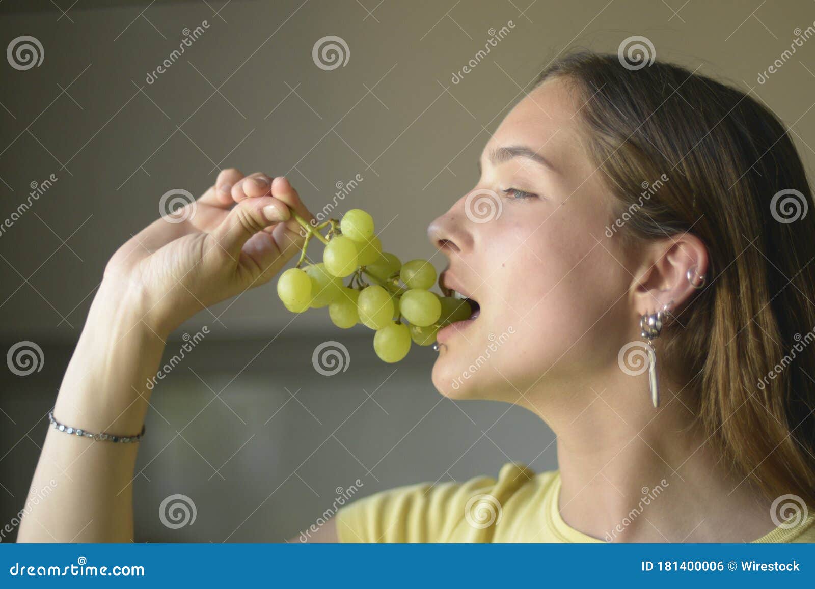 Shallow Focus Shot of a Female Biting on a Grape while Holding it Stock ...