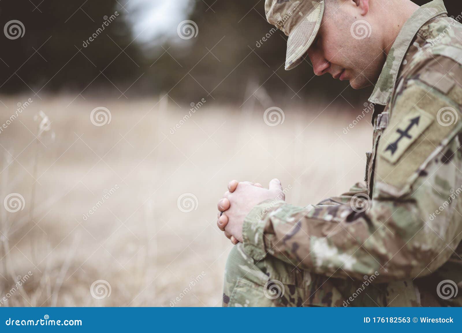Shallow Focus Shot of a Young Soldier Praying while Kneeling on a Dry ...