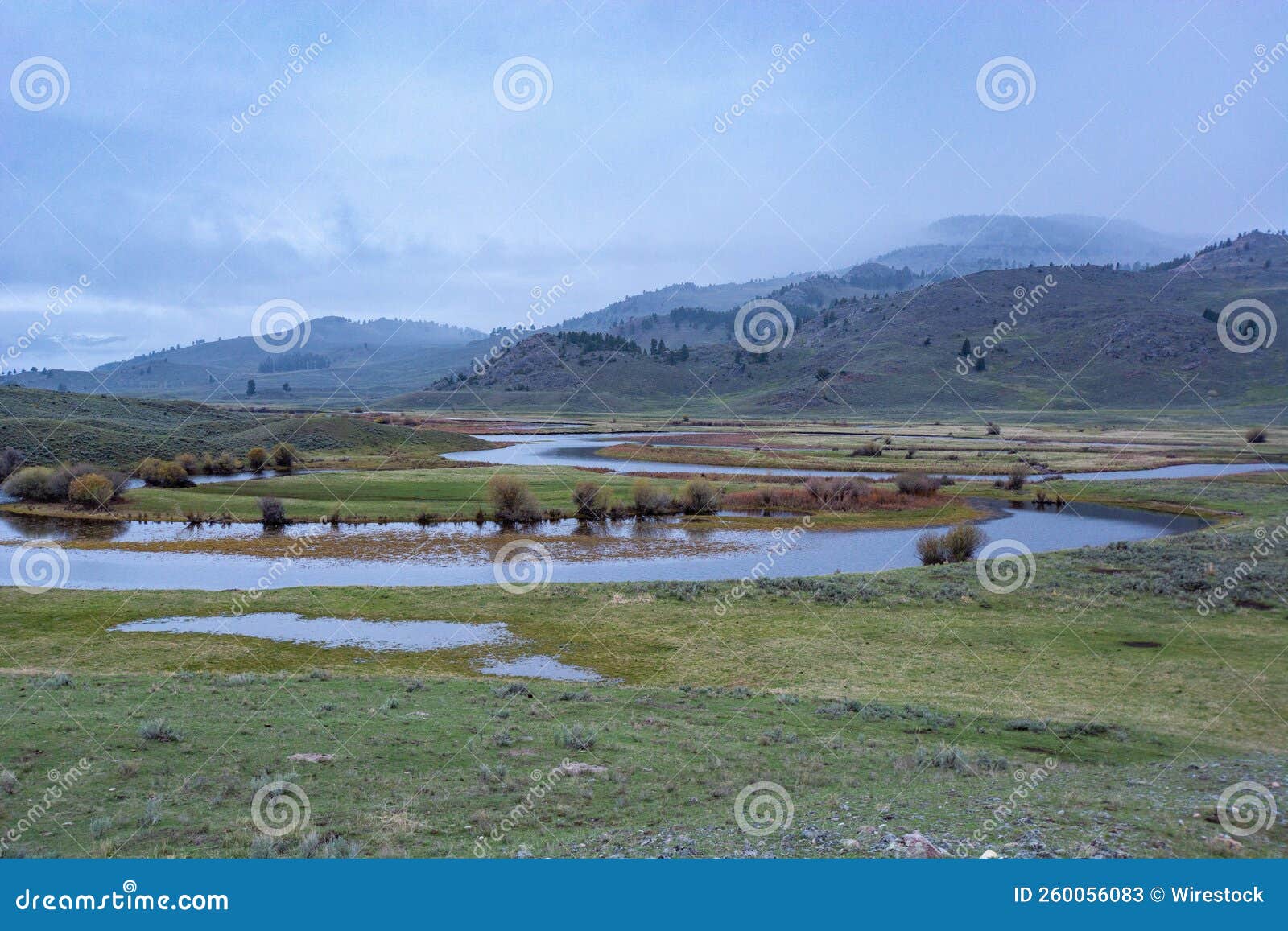 Shallow River Winding through the Greenery of the Field with Mountains ...