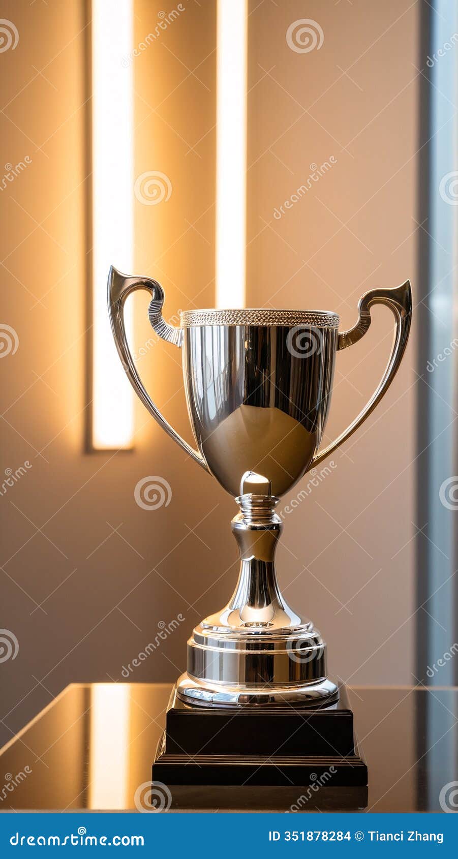 A Shiny Trophy with Two Handles Sits on a Reflective Surface ...