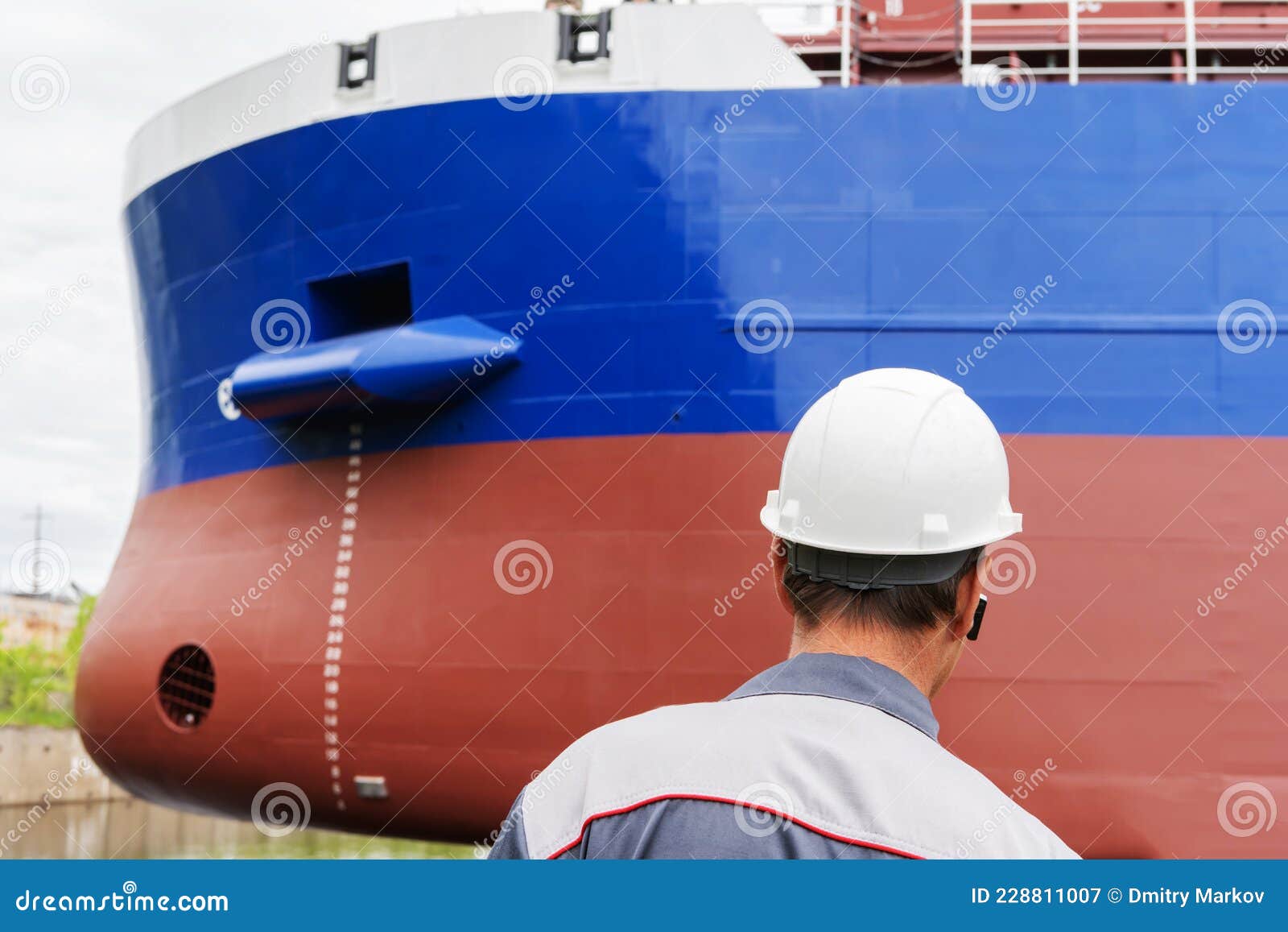 Shipyard. a Worker in Front of a Large Ship during Launching. Back View ...