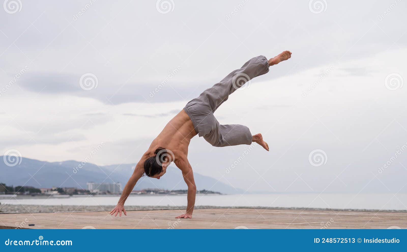 Shirtless Caucasian Man Doing Acrobatic Wheel on the Beach. Stock Image ...