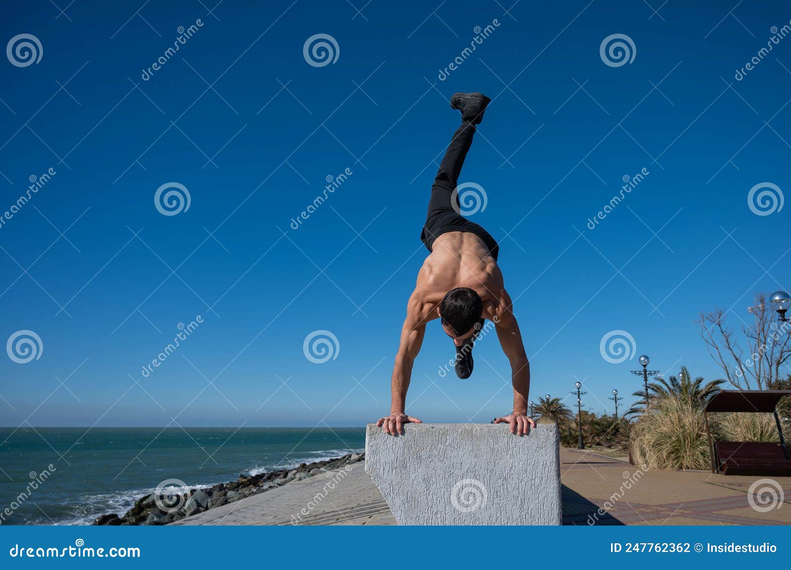 Shirtless Man Doing a Handstand on a Parapet by the Sea. Stock Photo ...