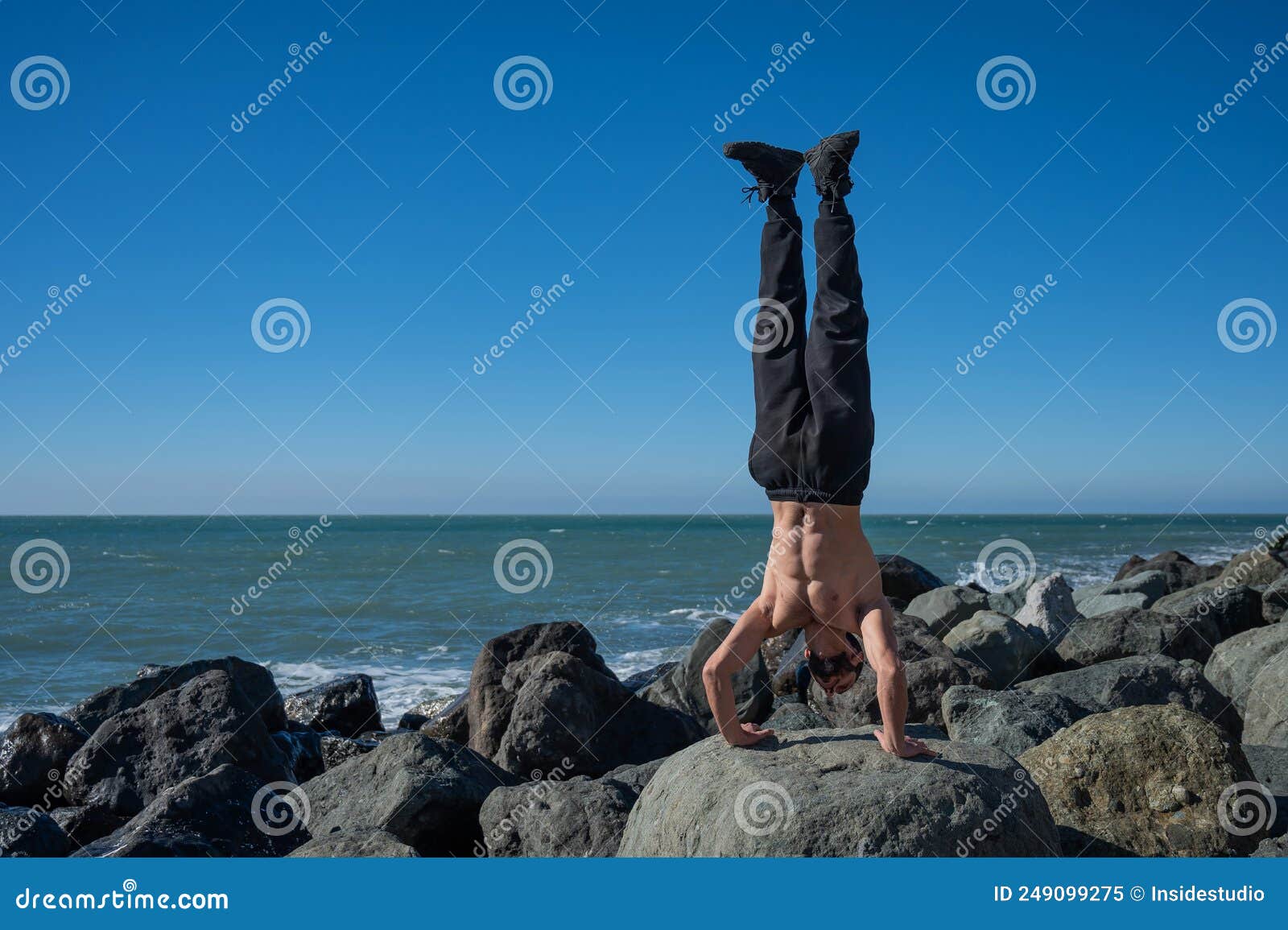 Shirtless Man Doing Handstand on Rocks by the Sea. Stock Image - Image ...