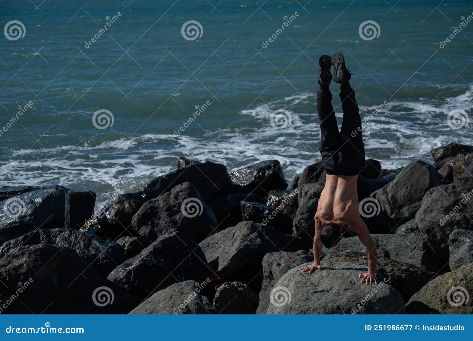 Shirtless Man Doing Handstand on Rocks by the Sea. Stock Image - Image ...