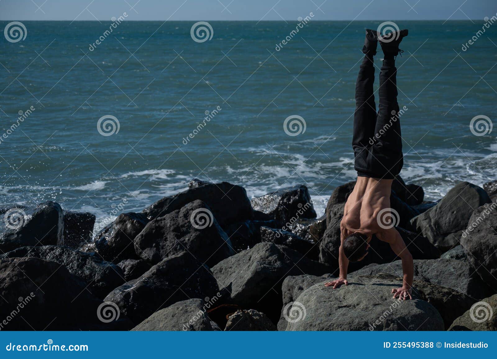 Shirtless Man Doing Handstand on Rocks by the Sea. Stock Photo - Image ...