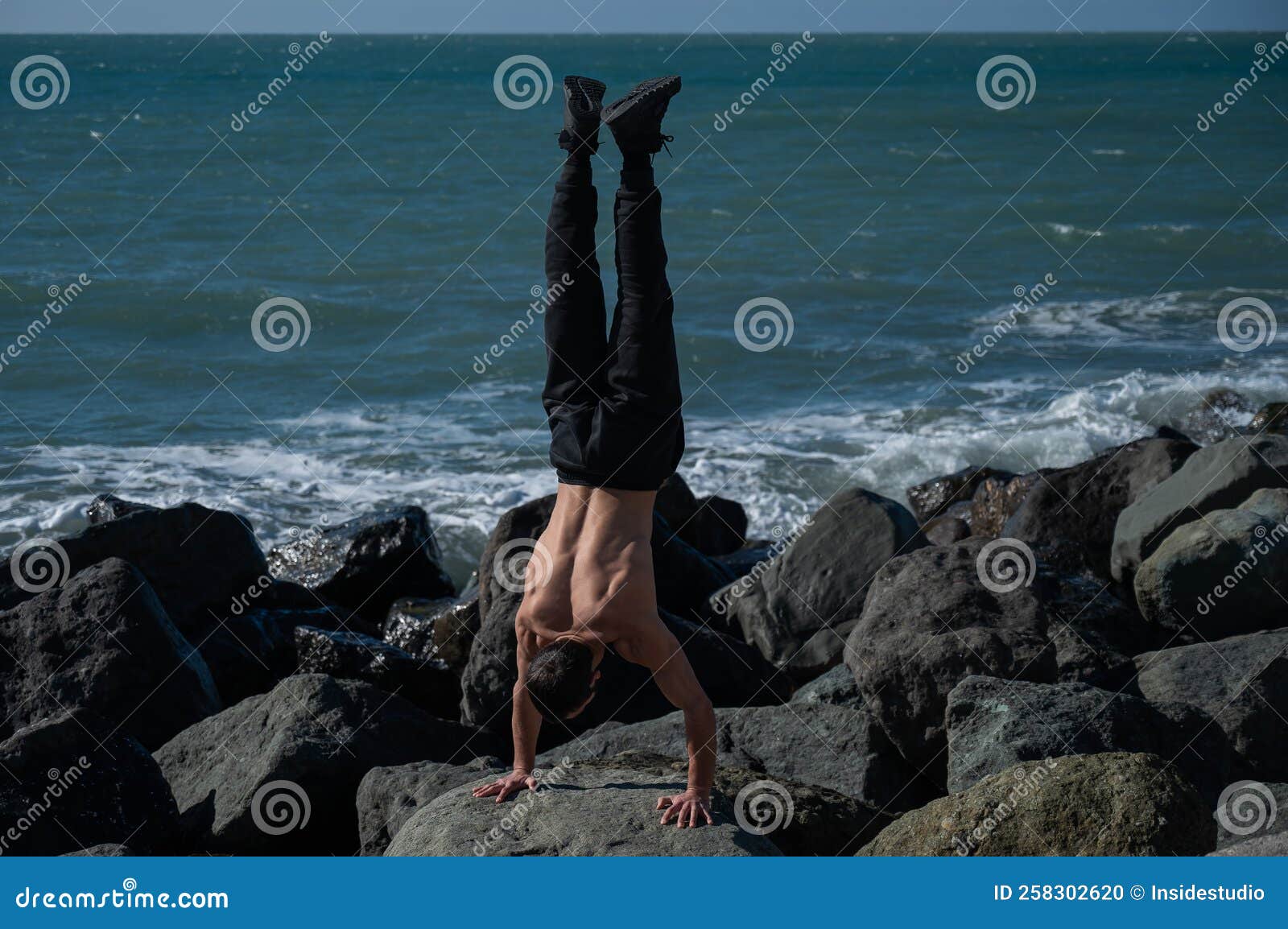 Shirtless Man Doing Handstand on Rocks by the Sea. Stock Photo - Image ...