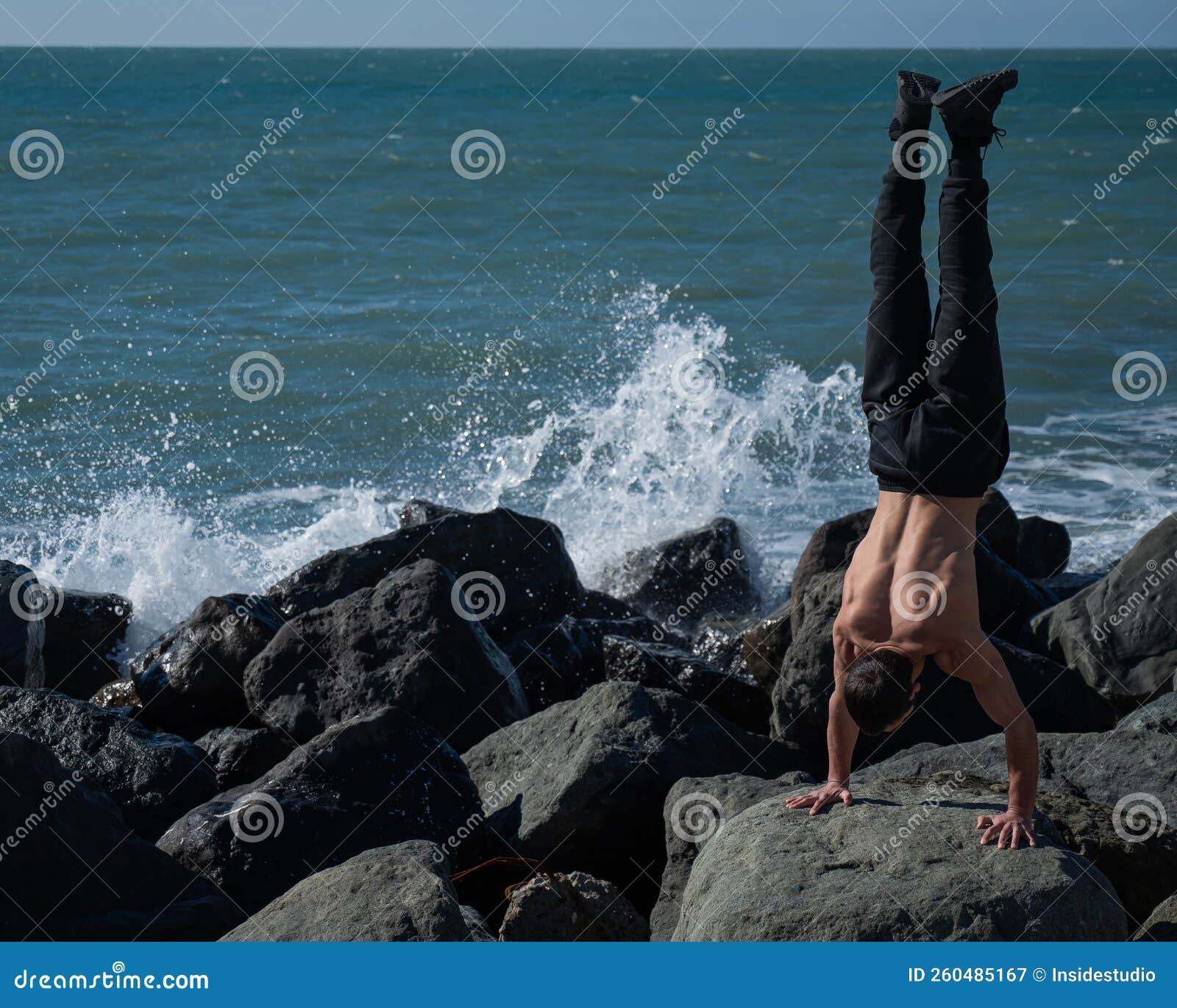 Shirtless Man Doing Handstand on Rocks by the Sea. Stock Image - Image ...