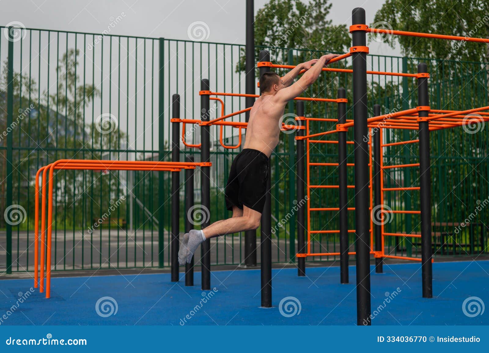 A Shirtless Man is Doing a Workout on the Horizontal Bars Outdoors ...