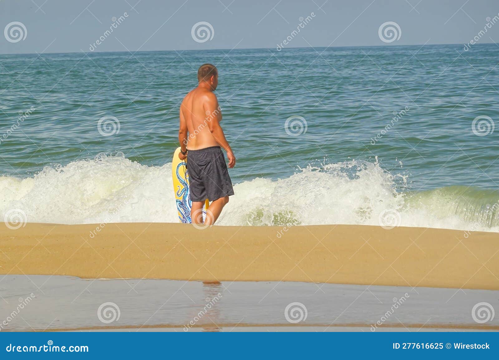 Shirtless Man Walking on a Sandy Beach, Getting Ready To Surf in the ...