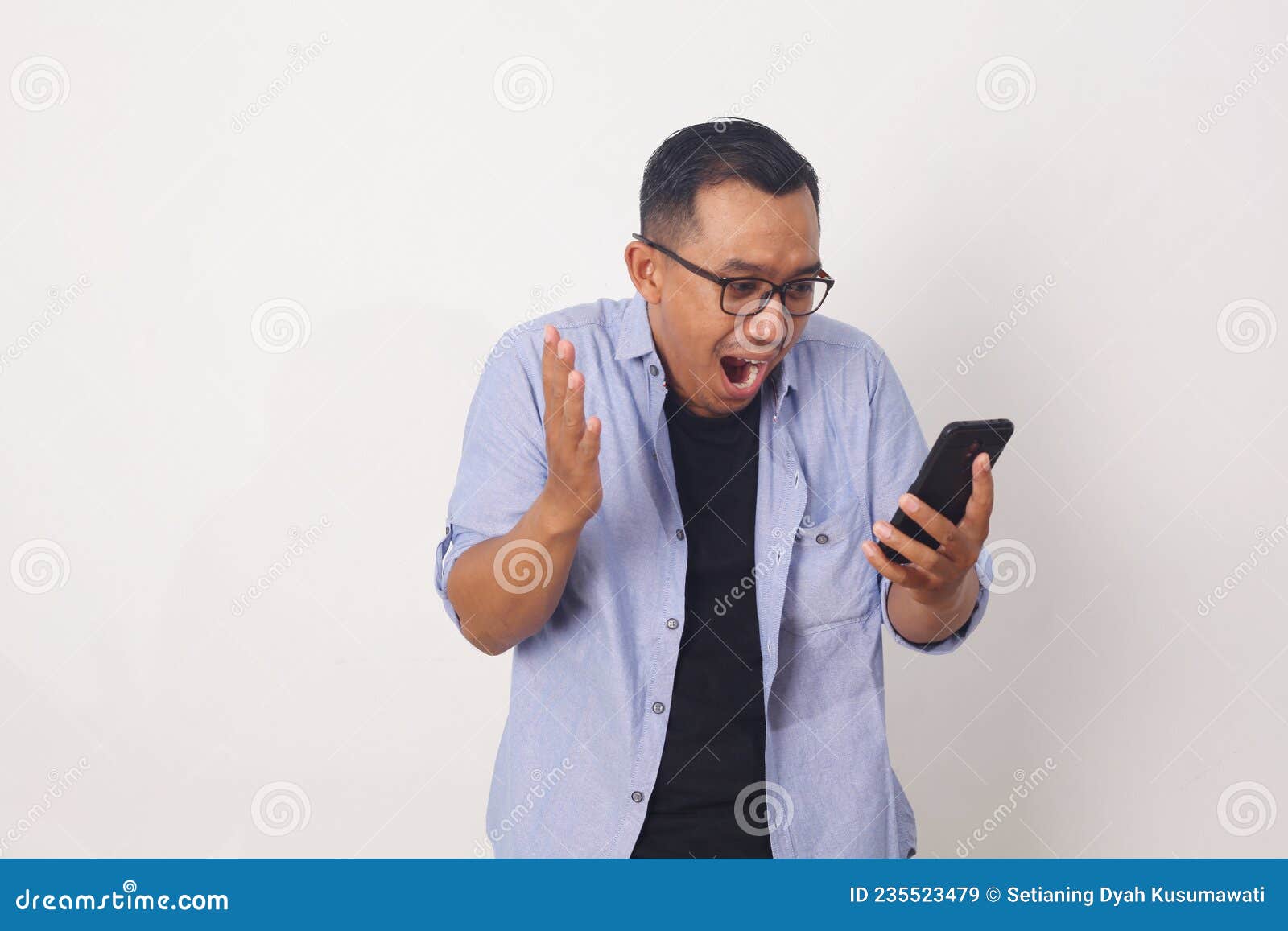Shocked Asian Man While Looking At Mobile Phone Isolated On White