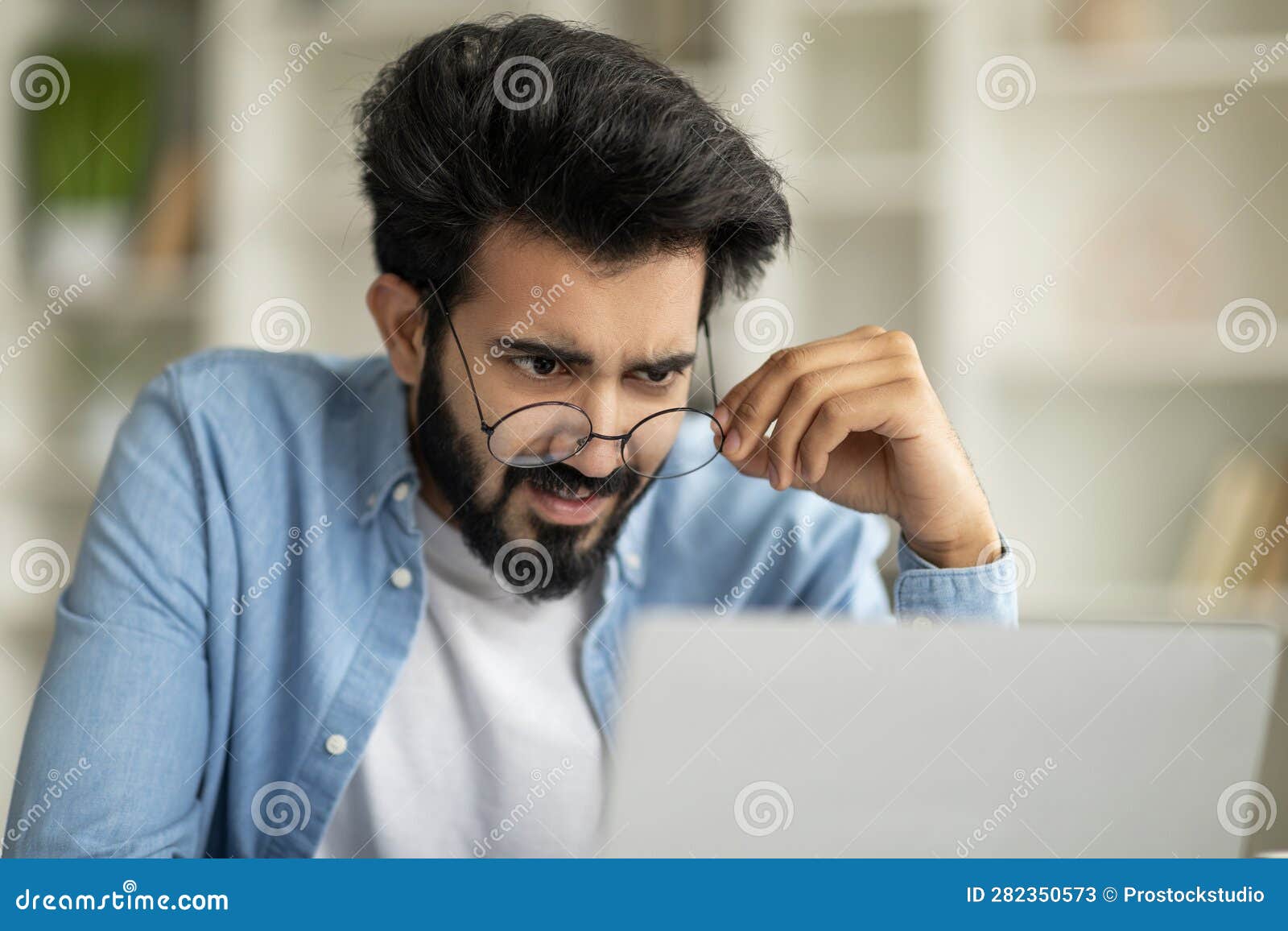 Shocked Indian Freelancer Guy Taking Off Glasses And Looking At Laptop